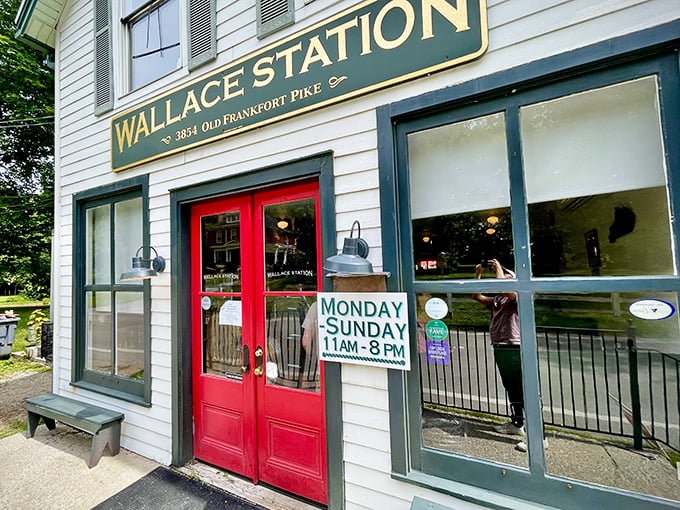 The iconic white clapboard exterior of Wallace Station beckons like an old friend with its cheerful red door and golden sign. Kentucky hospitality in architectural form.