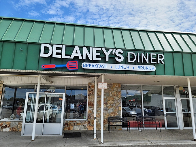 The distinctive green roof and stone facade of Delaney's Diner stands as a beacon for breakfast enthusiasts. That spatula sign promises delicious things await inside.