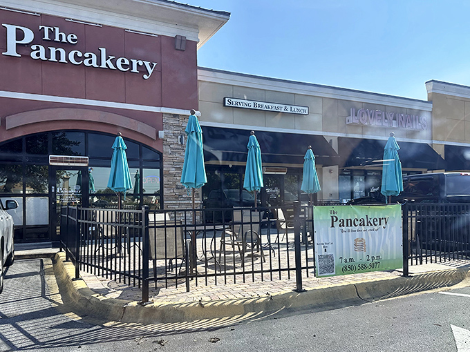 The Pancakery's cheerful exterior with turquoise umbrellas beckons like a breakfast beacon on Panama City Beach's busy strip. Resistance is futile.