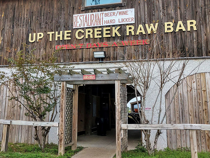 The weathered wooden exterior of Up The Creek Raw Bar stands like a salty sea captain, promising treasures of the Gulf within those humble walls.