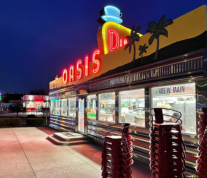 By night, the Oasis transforms into a glowing time capsule, its neon signs beckoning road-weary travelers with promises of comfort food and nostalgic charm.