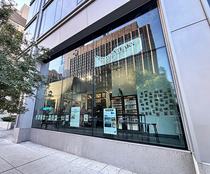 Shay's Steaks gleams like a modern oasis amid Philadelphia's urban landscape, its sleek glass storefront promising culinary treasures within.