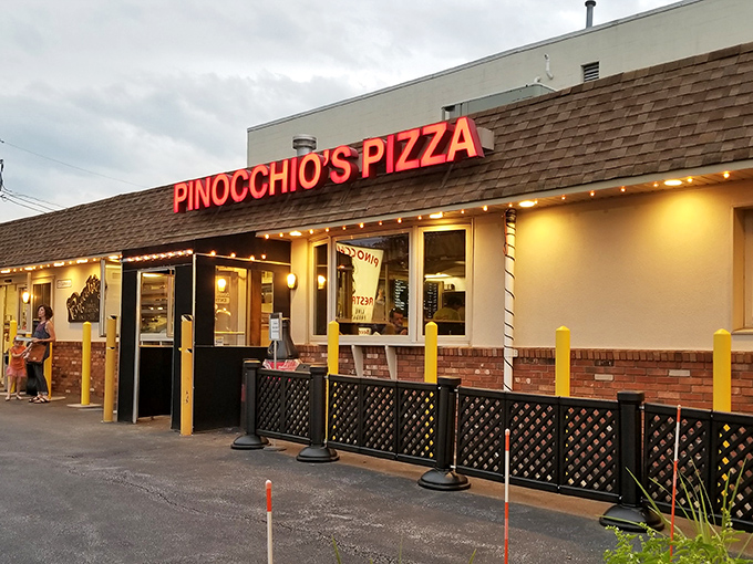 As dusk settles, Pinocchio's red neon sign glows like a lighthouse for the pizza-obsessed. Those yellow posts aren't just functional&mdash;they're guarding culinary treasure.
