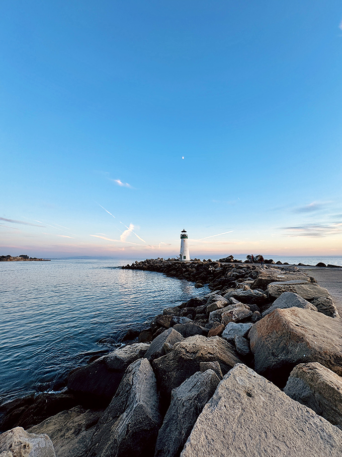 The quintessential California postcard moment: Walton Lighthouse standing proudly on its rocky perch, where the Santa Cruz Harbor meets the vast Pacific.