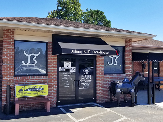 The unassuming brick exterior of Johnny Bull's Steakhouse, complete with its iconic bull statue, proves that culinary greatness doesn't need flashy packaging.