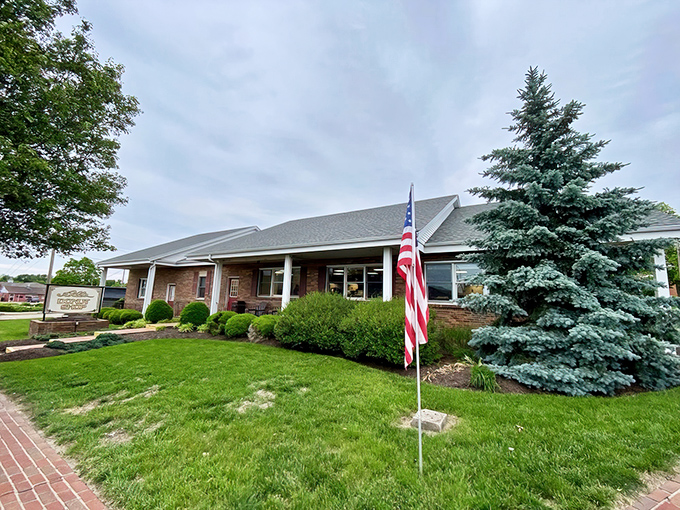 This brick shop, framed by lush greenery and a proud American flag, warmly welcomes visitors with small-town charm.