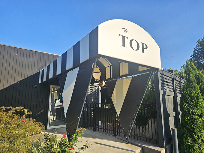 The iconic black and white striped entrance of The Top Steakhouse stands like a mid-century time portal to the golden age of American dining.