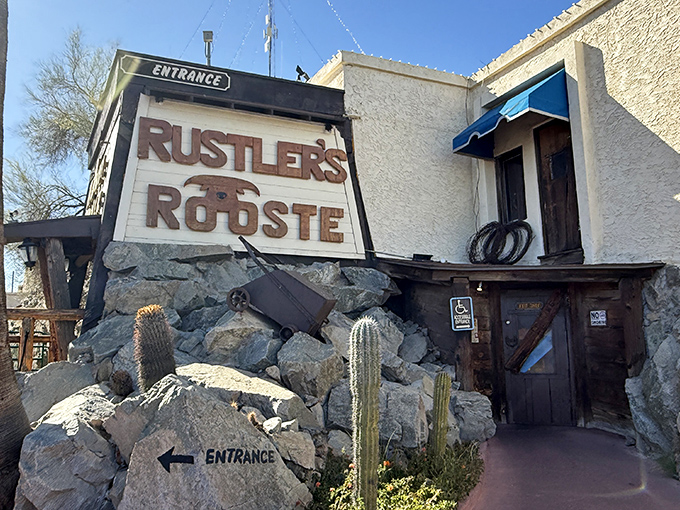 The rugged stone entrance to Rustler's Rooste stands like a Western movie set come to life, complete with desert cacti and that iconic sign promising adventure.