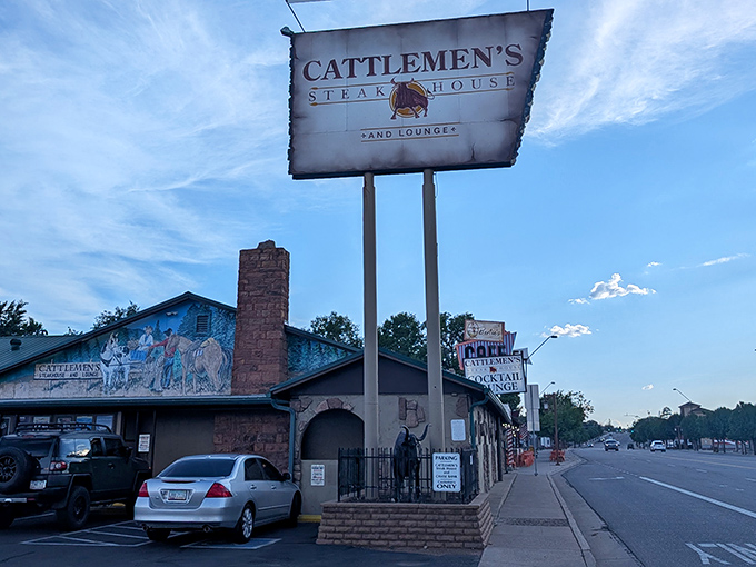 The unassuming exterior of Cattlemen's Steakhouse & Lounge, where that stone chimney has witnessed countless Arizona sunsets and satisfied diners heading home with full bellies.