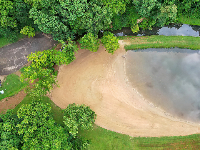 Aerial serenity! Pine Lake's sandy beach creates a perfect crescent against the emerald forest, like nature's own amphitheater for swimming adventures.
