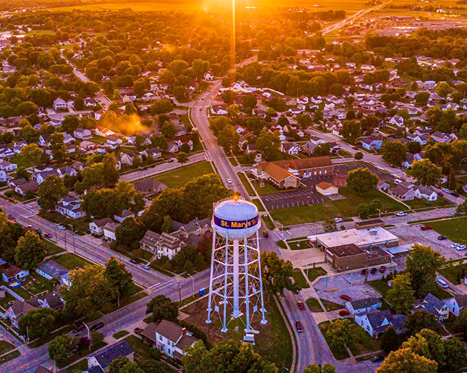 The iconic St. Marys water tower stands sentinel over a community bathed in golden sunset light, where neighbors still know each other by name.