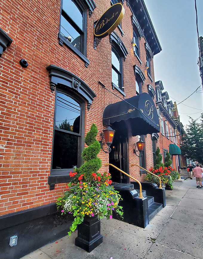 The historic brick fa&ccedil;ade of The Belvedere Inn welcomes visitors with elegant black awnings and vibrant flower boxes, a Victorian beauty in Lancaster's urban landscape.