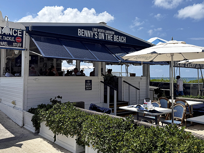 Benny's white beach shack exterior with blue awnings isn't trying to impress you—until you taste what's inside and realize you've found Florida's seafood mothership.
