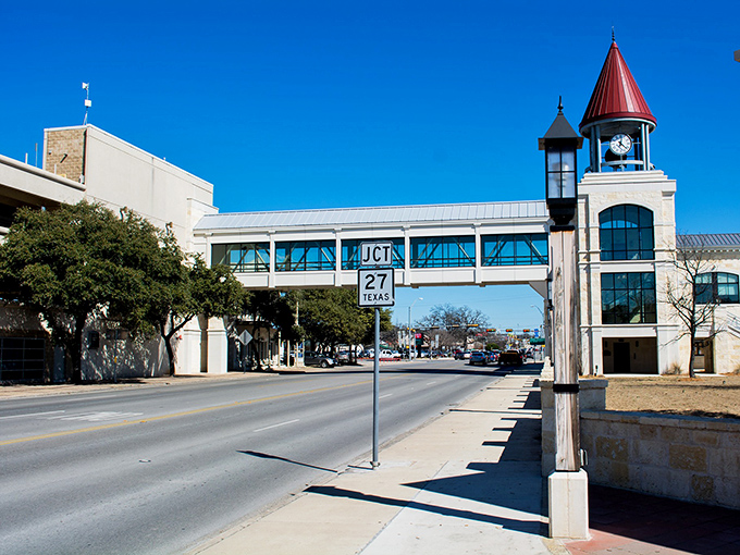 The iconic clock tower pedestrian bridge connects Kerrville's downtown areas, offering both functionality and a distinctive architectural landmark against that brilliant Texas sky.