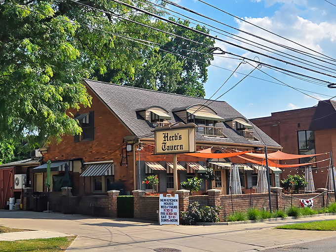 Herb's Tavern welcomes you with classic brick charm and cheerful red umbrellas &ndash; like finding a neighborhood gem you've been missing your whole life.