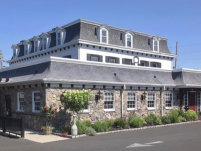 The historic stone facade of Spring House Tavern stands proudly against the Pennsylvania sky, promising culinary treasures within its centuries-old walls.