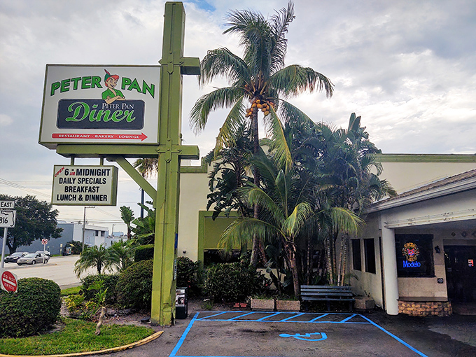 The iconic green-pillared entrance to Peter Pan Diner stands like a beacon of breakfast hope amid the palm trees of Oakland Park.