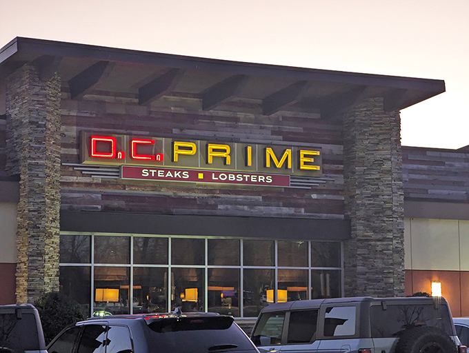 As dusk settles, DC Prime's distinctive red and yellow signage glows with the warm invitation of a steakhouse that takes its beef seriously.