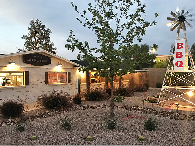The unassuming exterior of Caldwell County BBQ with its iconic windmill sign standing tall &ndash; Texas pride in the Arizona desert.