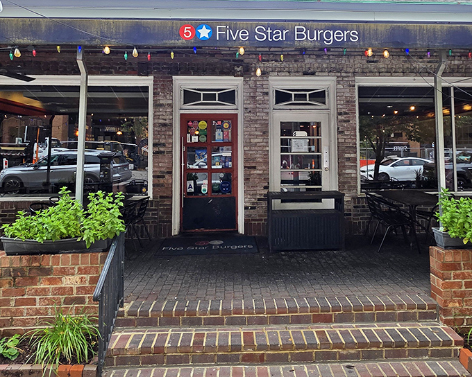 The charming brick exterior of 5 Star Burgers beckons with colorful string lights and lush greenery, like a burger oasis in Clayton's urban landscape.