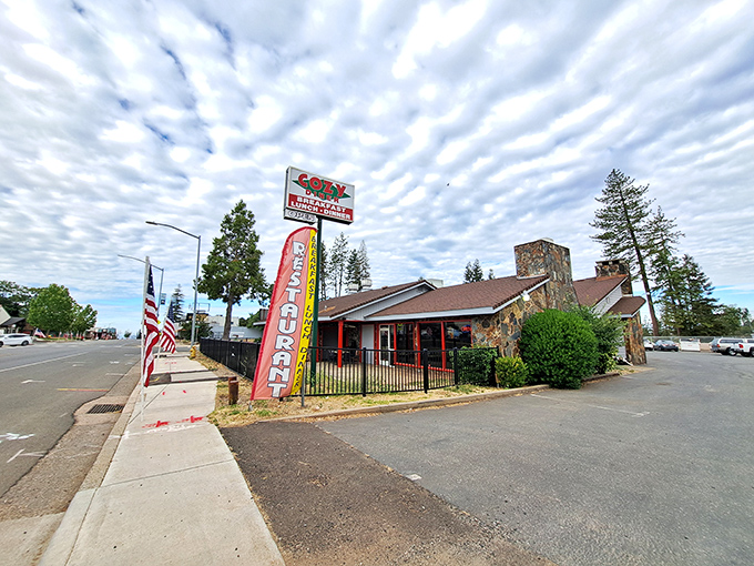 A slice of Americana under dramatic skies. The stone-and-brick exterior of Cozy Diner stands like a culinary lighthouse, beckoning hungry travelers with its unmistakable roadside charm.