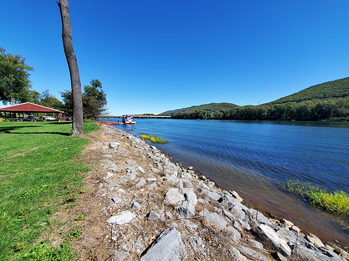 Nature's perfect amphitheater: rolling hills embrace the river's curve while a red pavilion promises picnic perfection away from the digital world.