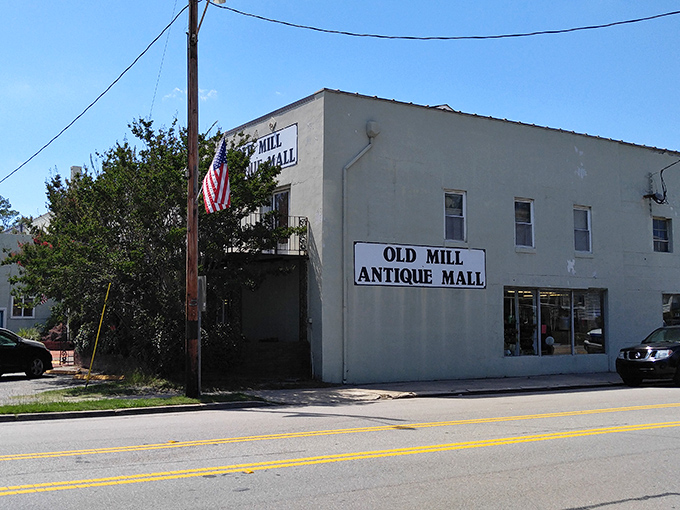 The unassuming exterior of Old Mill Antique Mall - where treasures hide behind brick walls and modest signage, like a poker player with a royal flush saying nothing.