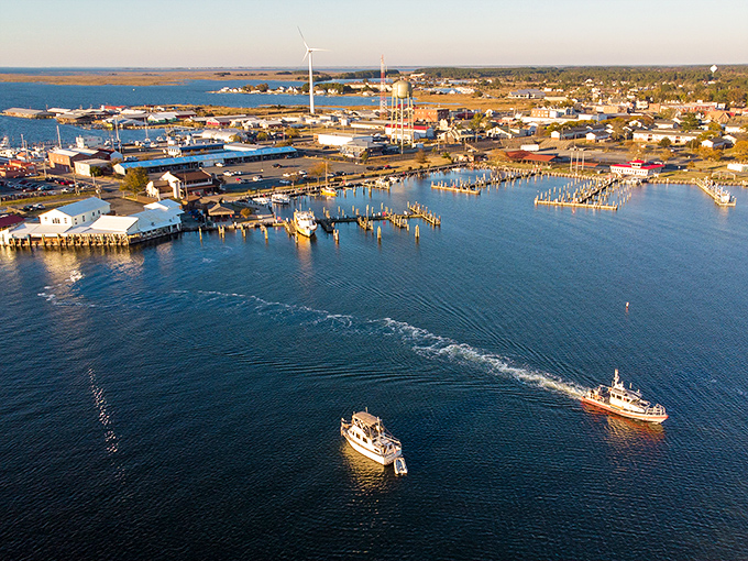 Crisfield's harbor at golden hour reveals its true identity&mdash;a working waterfront where fishing boats return with the day's bounty while modern wind turbines stand sentinel in the distance.