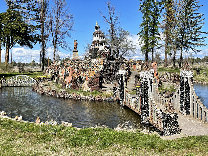 Where fantasy meets geology&mdash;a miniature stone castle and Statue of Liberty stand proudly beside a handcrafted bridge spanning peaceful waters.