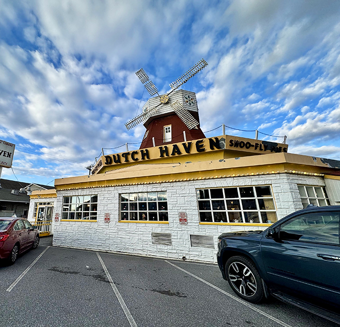 From another angle, the charming white stone building with its distinctive red windmill creates the perfect roadside photo opportunity.