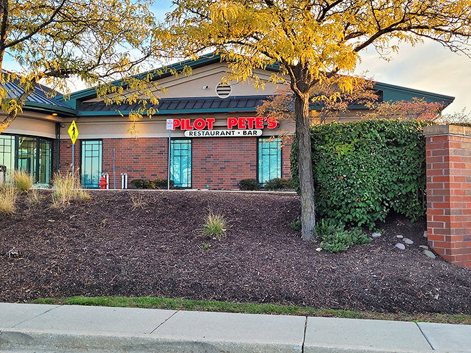 The exterior of Pilot Pete's welcomes you like an old friend, its brick facade and bold red signage promising aviation adventures and culinary delights beneath autumn's golden canopy.
