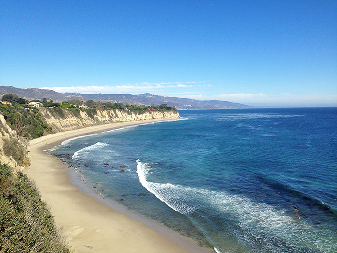 The curve of Point Dume's shoreline looks like nature's perfect smile, with the Pacific's blue waters meeting golden California sand in a timeless embrace.