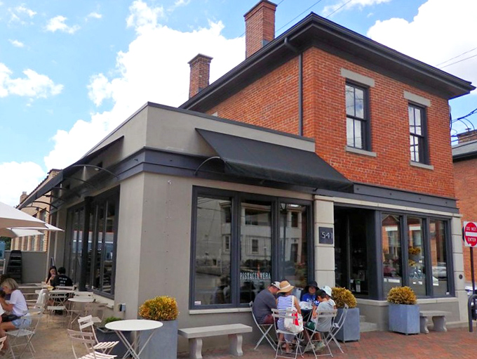 Sunlight bathes the outdoor seating area, where lucky patrons savor their treasures amid the historic brick streets of Columbus.