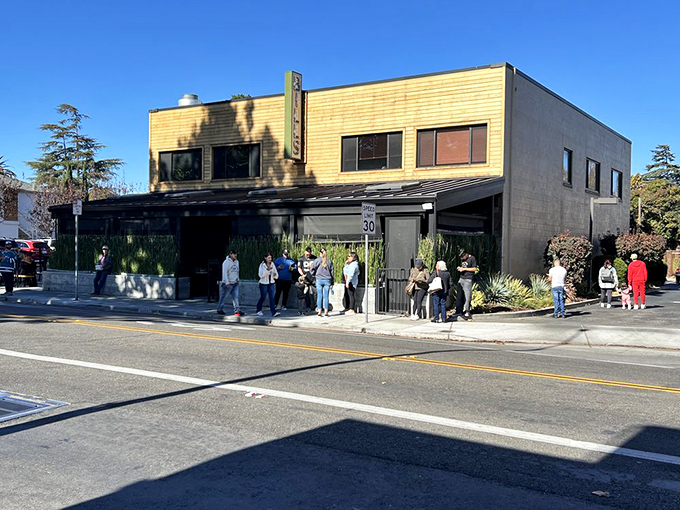 The iconic yellow and gray exterior of Bill's Caf&eacute; stands like a beacon of breakfast hope on Willow Street, complete with a line that speaks volumes about what awaits inside.
