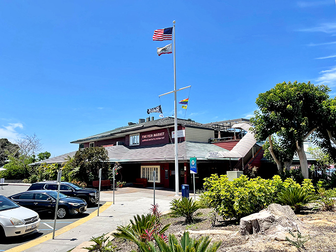 The Fish Market stands proudly against San Diego's blue sky, flags fluttering in the ocean breeze &ndash; a maritime beacon for seafood lovers seeking authentic coastal flavors.