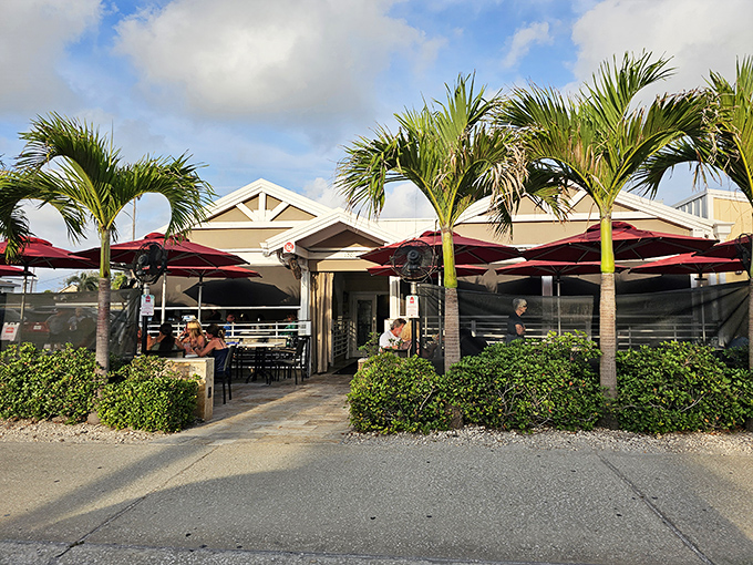 Palm trees stand guard at Guppy's entrance, their burgundy umbrellas creating islands of shade perfect for savoring seafood while Florida sunshine dances nearby.