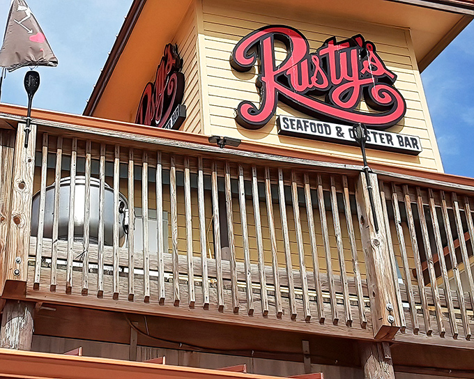 The iconic red cursive sign welcomes seafood lovers like a beacon of deliciousness. Rusty's weathered wooden deck promises authentic coastal experiences without pretension.