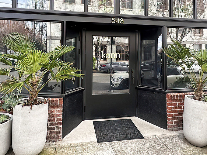 Kann's sleek exterior beckons with tropical palm sentinels standing guard. The modern black fa&ccedil;ade with "548" prominently displayed offers a stylish Portland welcome.