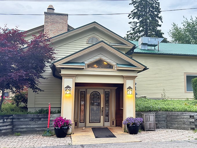 The charming farmhouse exterior of The Grill House welcomes you like an old friend, complete with colorful flower pots that say "come on in, the prime rib's waiting."
