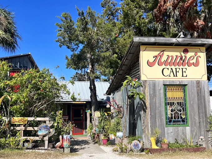 Annie's Cafe emerges from the Florida greenery like a storybook cottage, its weathered wood and yellow sign promising homestyle comfort just steps away.