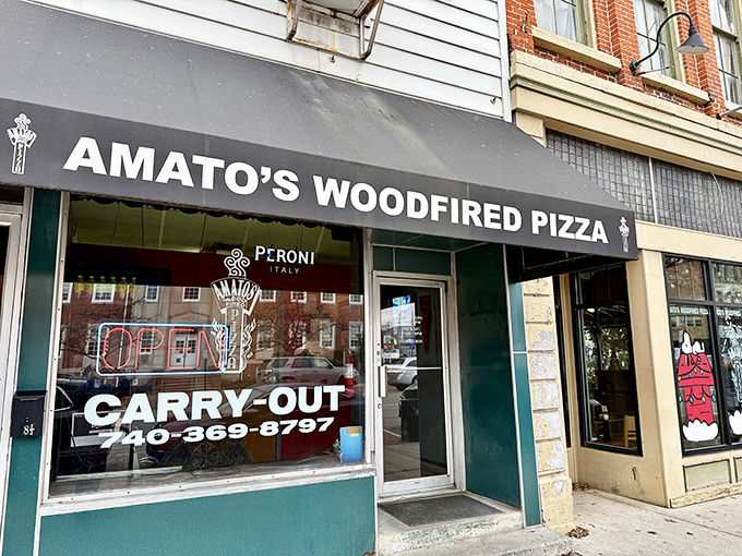 The unassuming storefront of Amato's beckons with its classic black awning and simple signage&mdash;proof that pizza paradise often hides in plain sight.