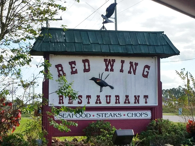 The rustic stone and wood exterior of Red Wing Restaurant stands like a culinary time capsule amid Groveland's lush Florida greenery.