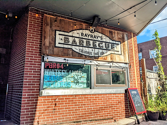 The unassuming brick exterior of Ray Ray's hides barbecue greatness like a superhero's secret identity. That wooden sign promises smoky treasures within.