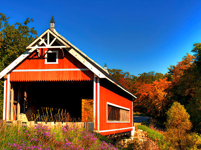 The Netcher Road Covered Bridge stands like a crimson sentinel against Ohio's blue skies, its classic design practically begging for a postcard moment.