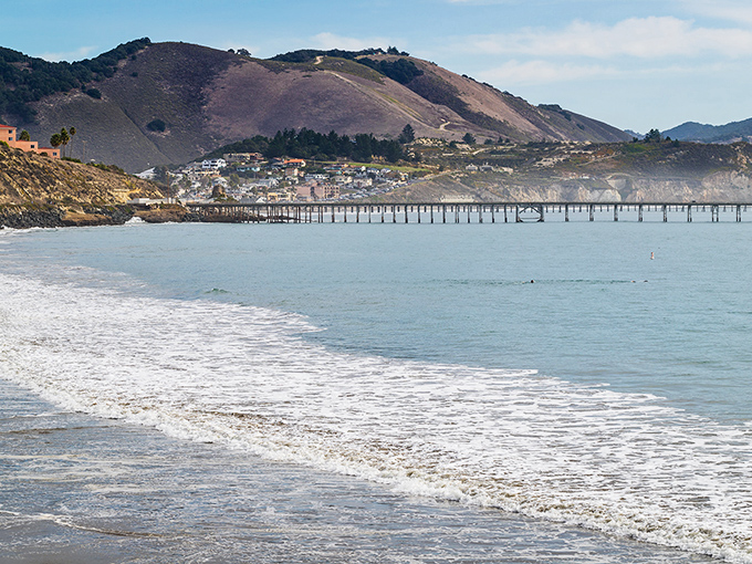 Avila Beach's historic pier stretches into the protected bay, where gentle waves meet golden shores beneath California's coastal hills.