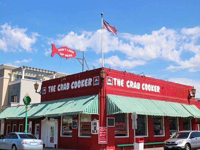 The iconic bright red exterior of The Crab Cooker stands out like a cheerful rebellion against Newport Beach's upscale aesthetic, complete with its famous fish-shaped "DON'T LOOK UP HERE" sign.