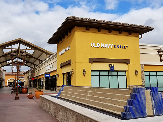 Old Navy's sunny yellow facade welcomes bargain hunters like a beacon of affordable fashion hope in the desert, promising treasures within its air-conditioned walls.