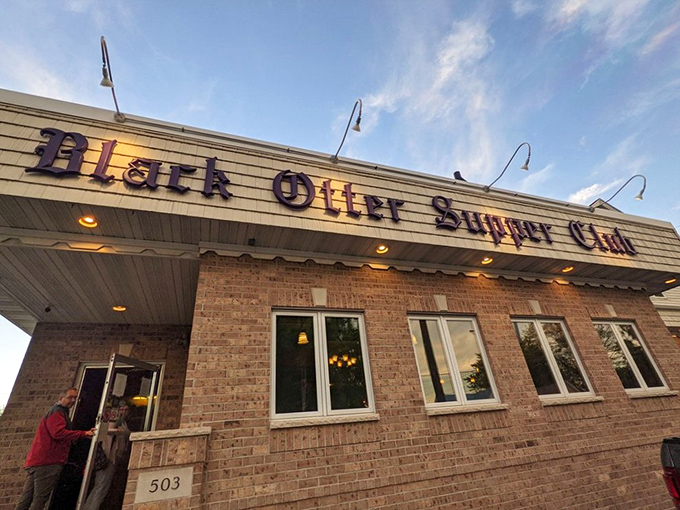 The iconic brick facade of Black Otter Supper Club beckons hungry travelers with its vintage sign and warm glow—Wisconsin's version of a culinary lighthouse.