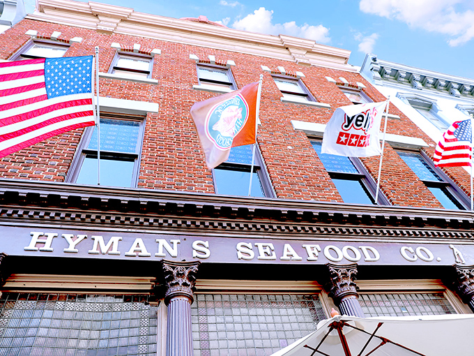 The historic brick façade of Hyman's Seafood stands proudly on Meeting Street, flags waving like a maritime welcome committee for hungry visitors.