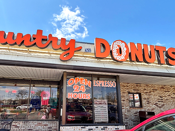 That "OPEN 24 HOURS" sign isn't just information—it's a promise. A brick-and-mortar love letter to those who understand that donuts are an anytime food.